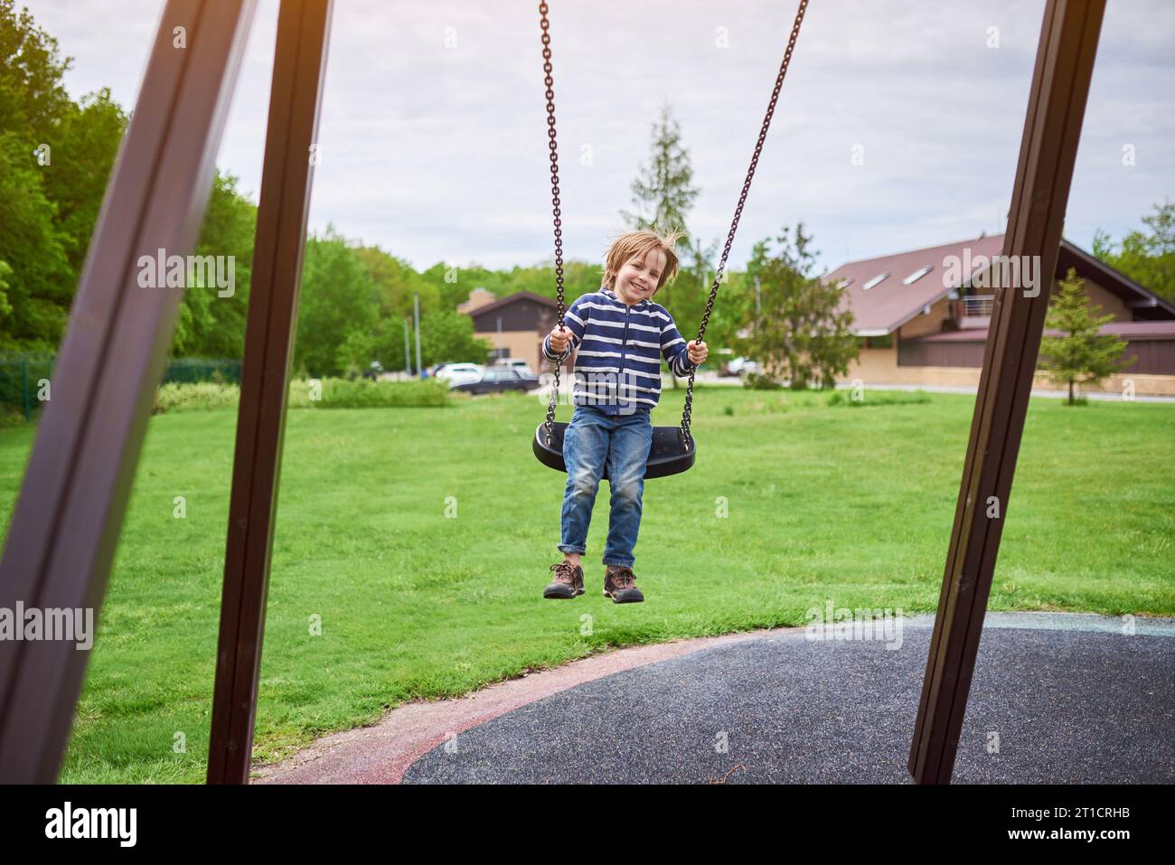 Outdoors portrait of cute preschool laughing boy swinging on a swing at ...
