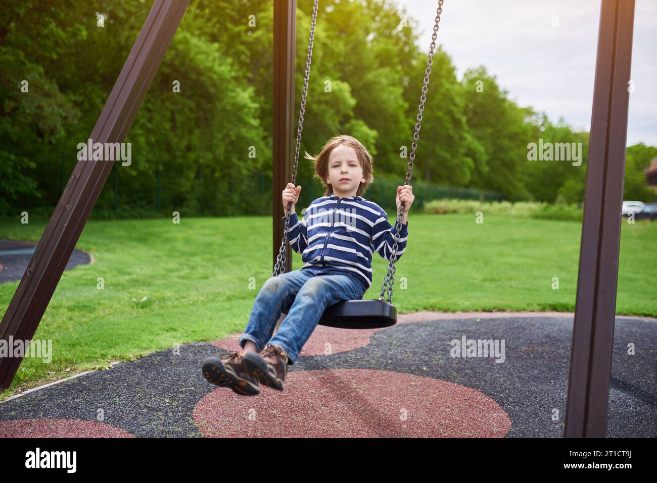 Outdoors portrait of cute preschool laughing boy swinging on a swing at ...