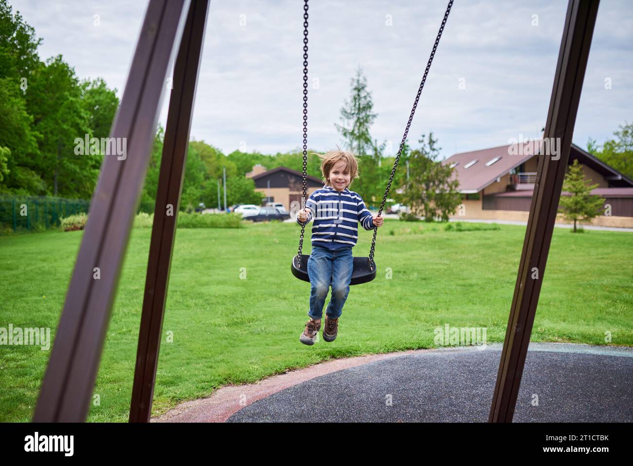 Outdoors portrait of cute preschool laughing boy swinging on a swing at ...