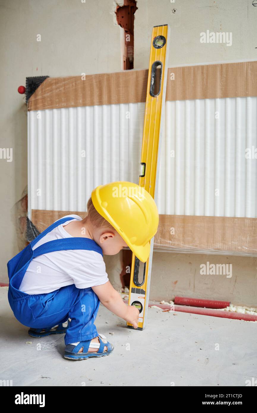 Child in safety helmet using spirit level ruler while installing ...