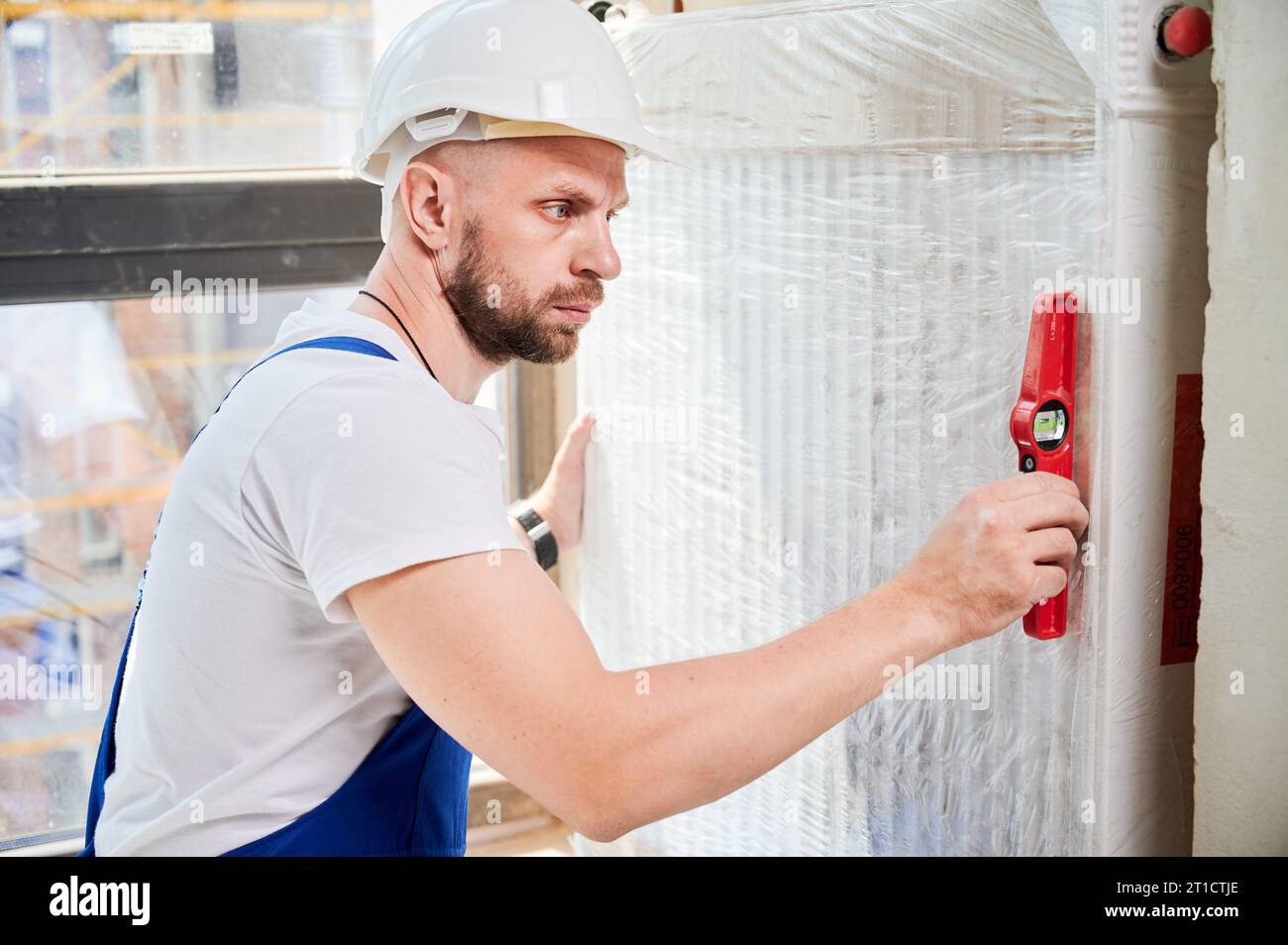 Male plumber in safety construction helmet using spirit level tool ...