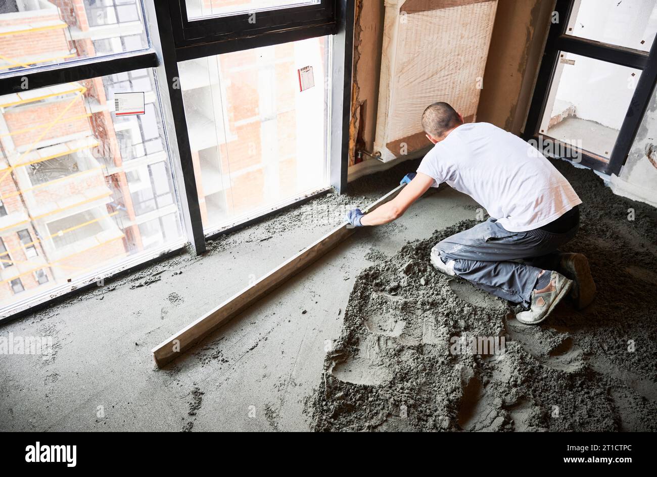 Man flattening and smoothing surface with straight edge in apartment ...