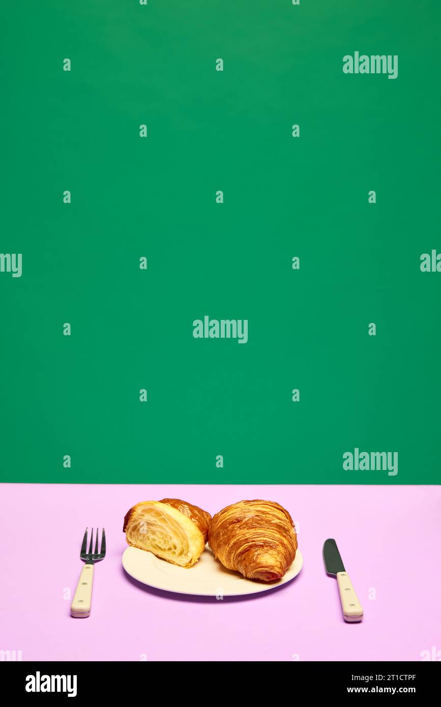 Crispy, fresh croissant, whole and cut in half lying on plater over ...