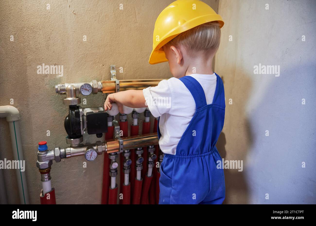 Baby boy checking plumbing installation with pipes and thermometer ...