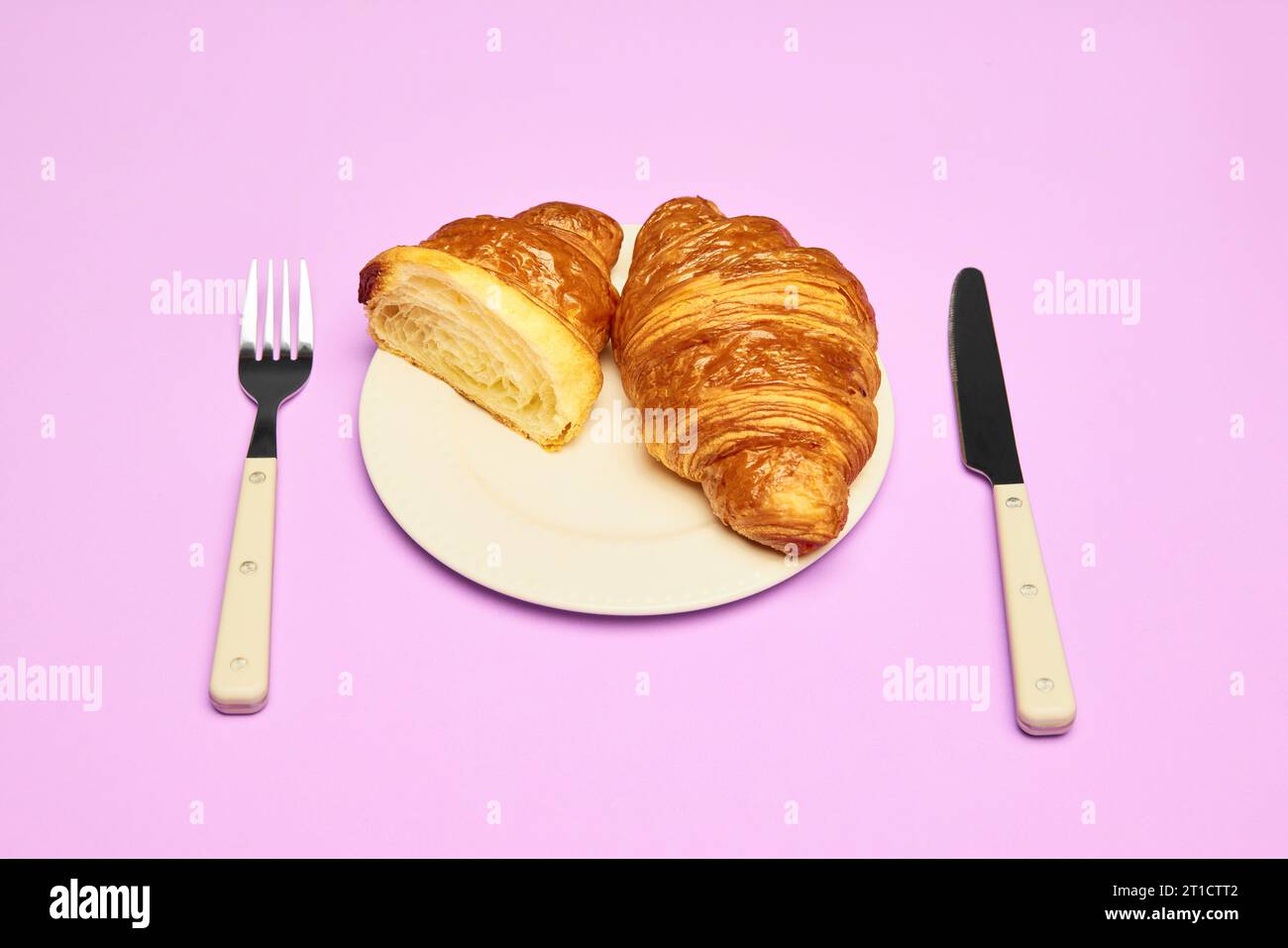 Crispy, fresh croissant, whole and cut in half lying on plater over ...