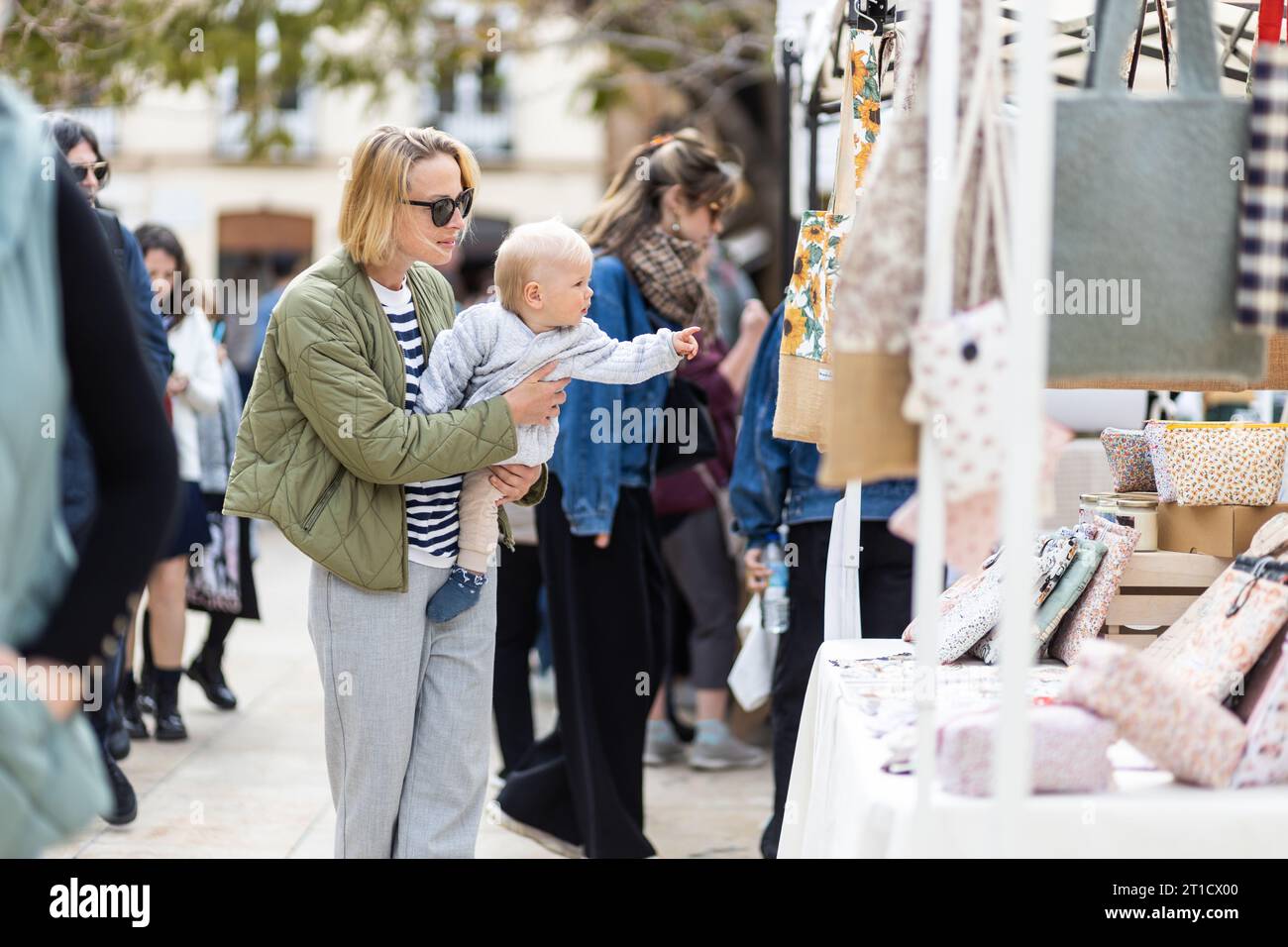 Mother walking carrying his infant baby boy child in crowd of people ...