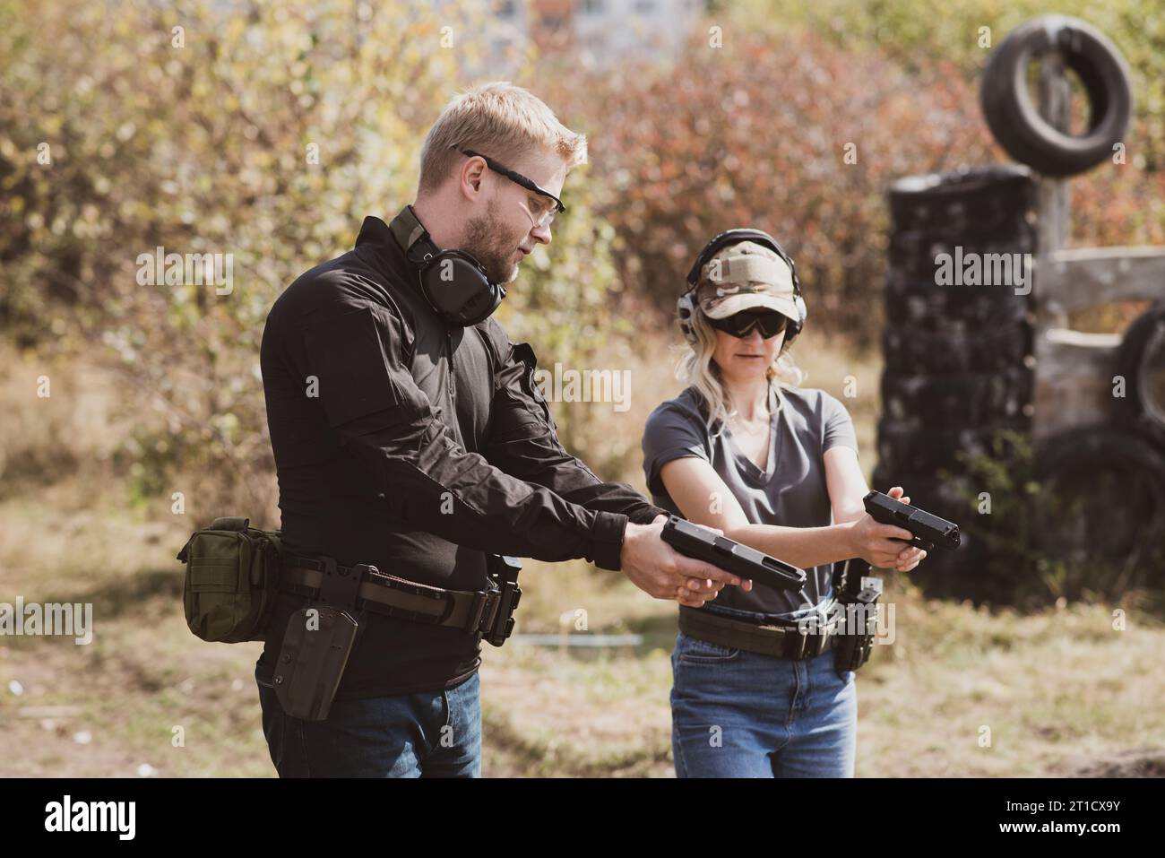 A woman learns to shoot a pistol at a shooting range with an instructor ...