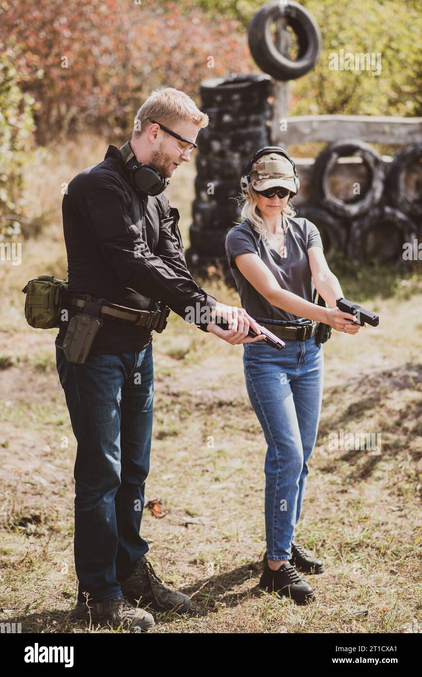 Shooting instructor teaching a woman how to properly handle a weapon at ...