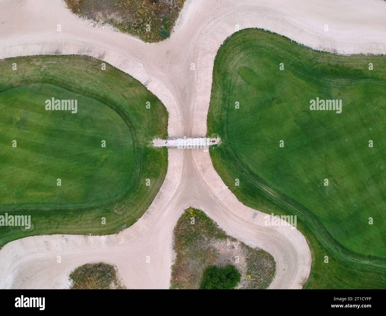 Aerial view of the green grass of the golf course. Bridge between hills ...