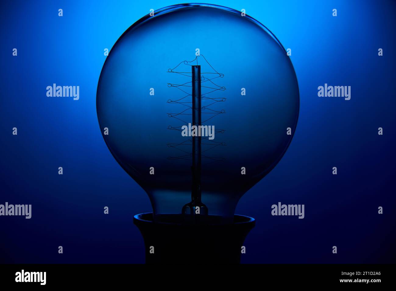 Extinguished electric vintage Edison light bulb with a spiral on a blue ...