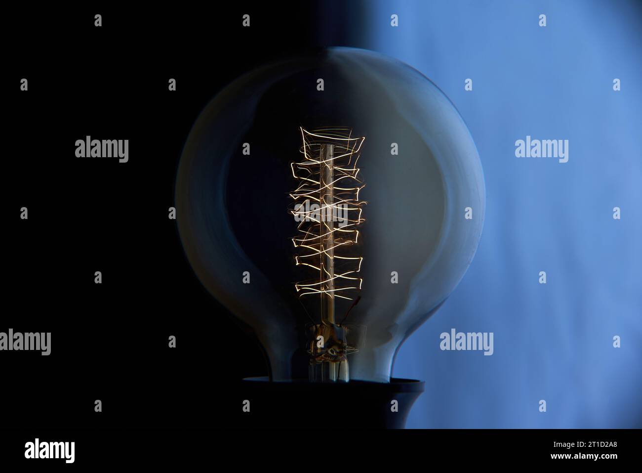 Electric vintage Edison light bulb with a spiral on a blue background ...