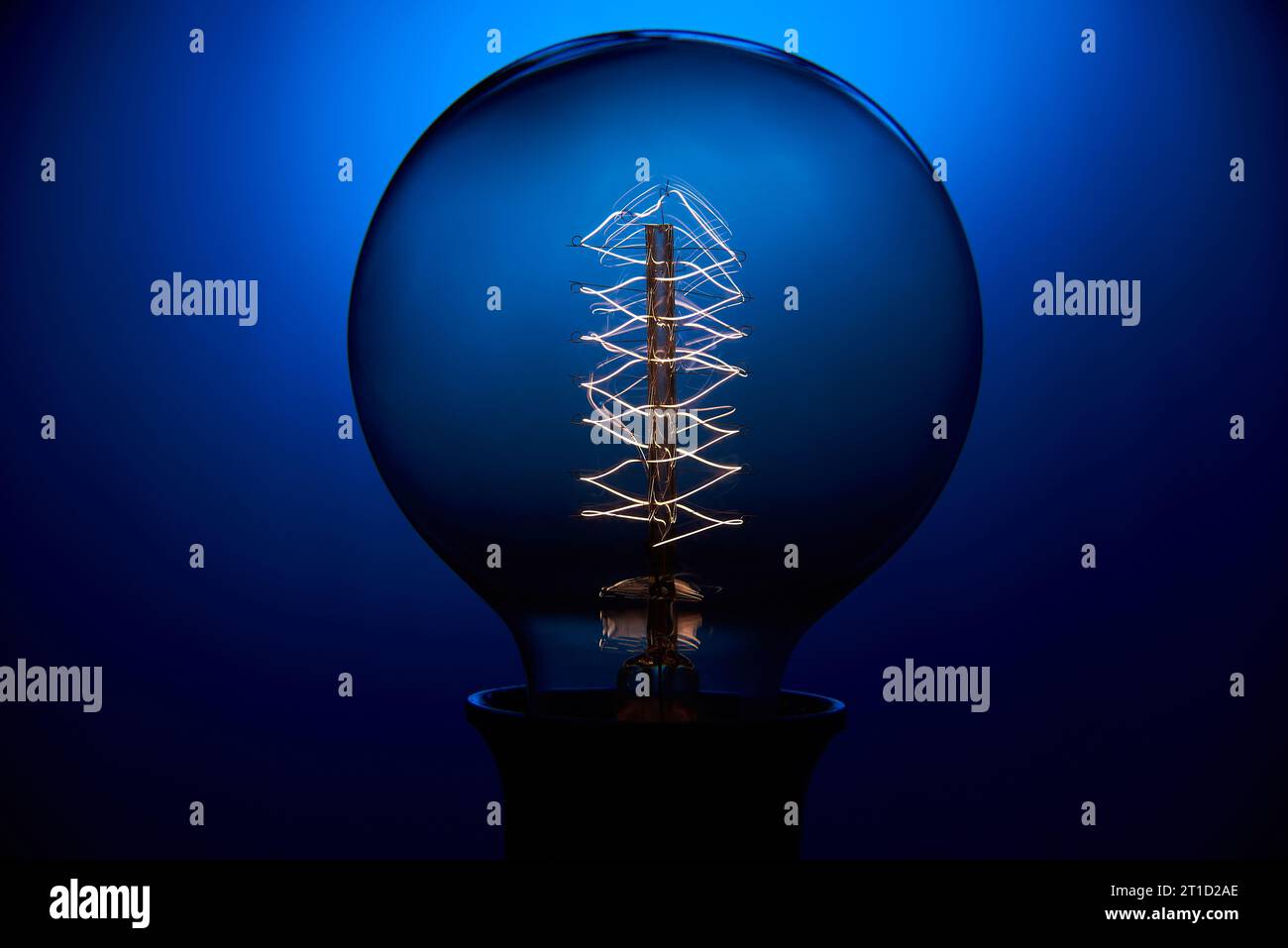 Electric vintage Edison light bulb with a spiral on a blue background ...