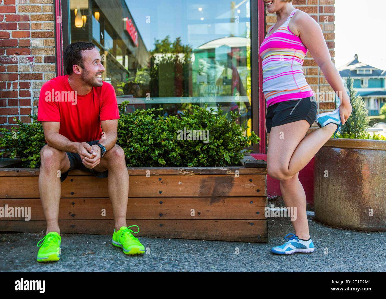 Two runners resting and one stretching in street, Seattle, Washington ...