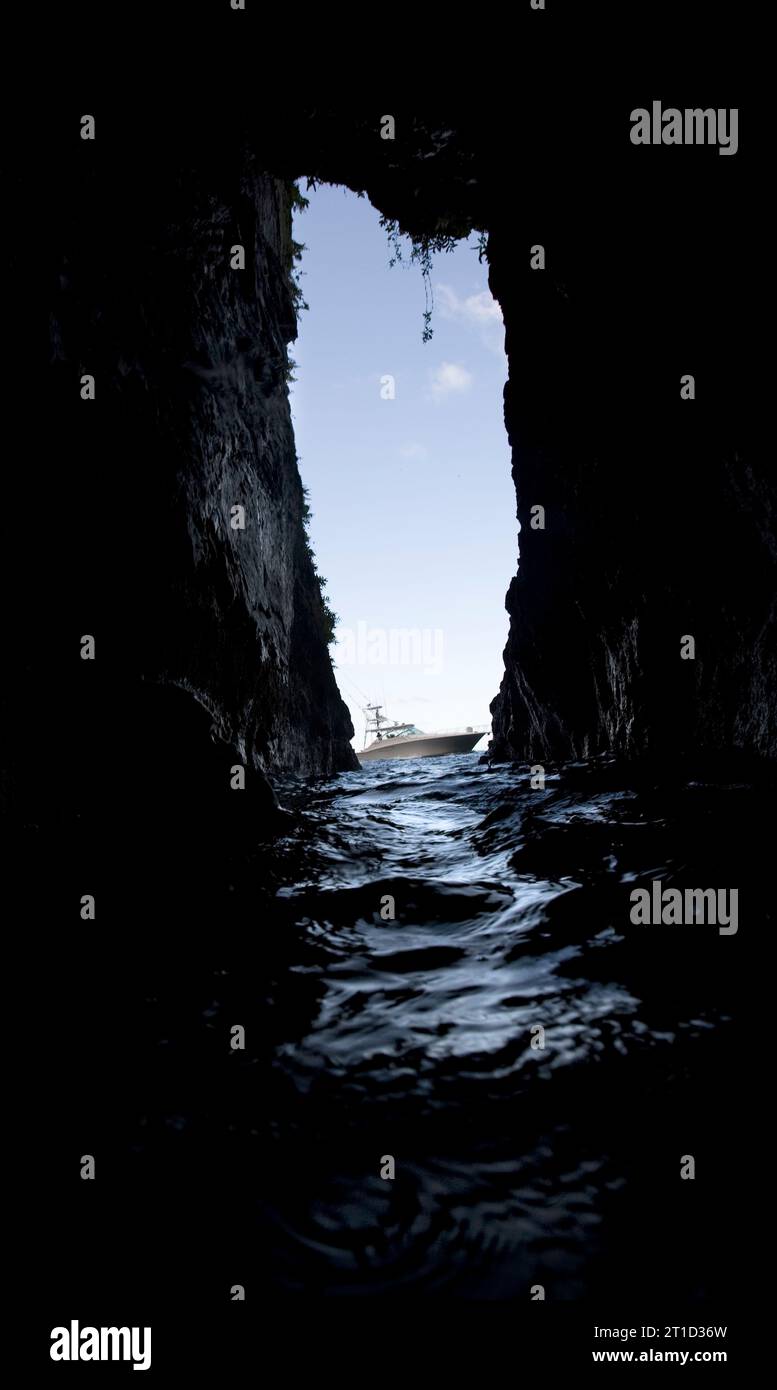 View of a boat floating in the water, through the narrow opening of a ...