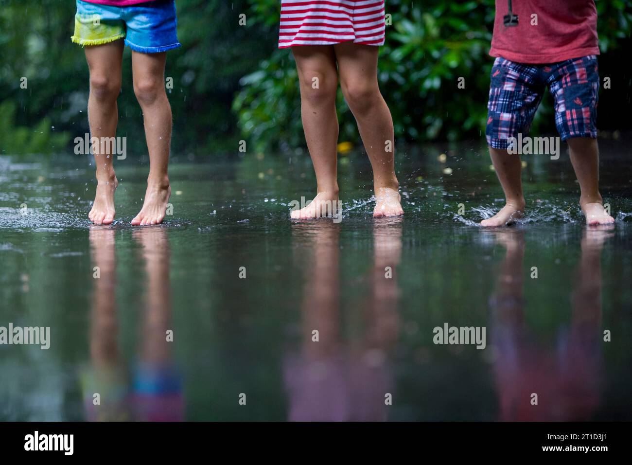 three young children spashing in the rain Stock Photo - Alamy