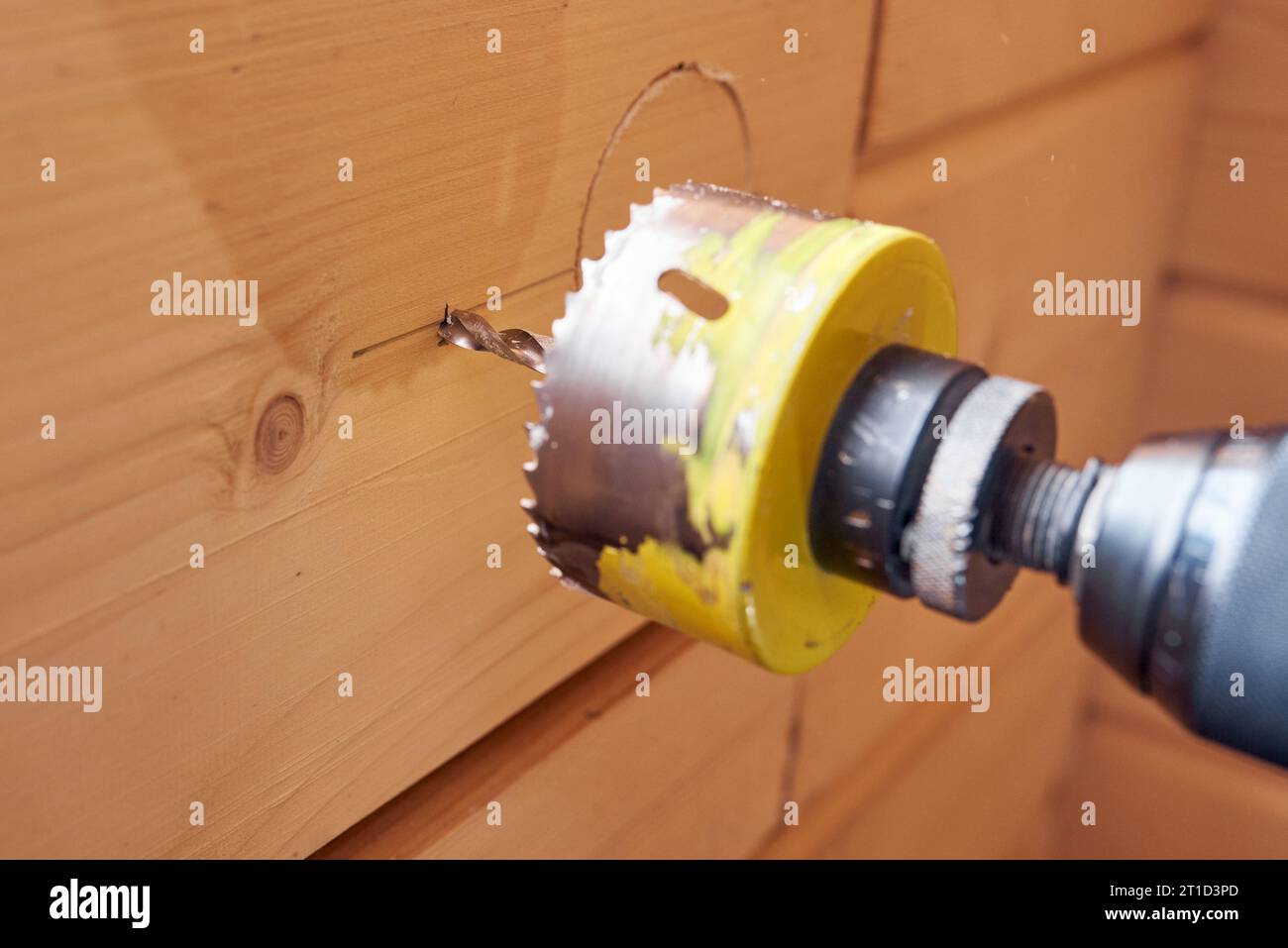 drill with crown making hole in wooden wall for electric cable, socket ...