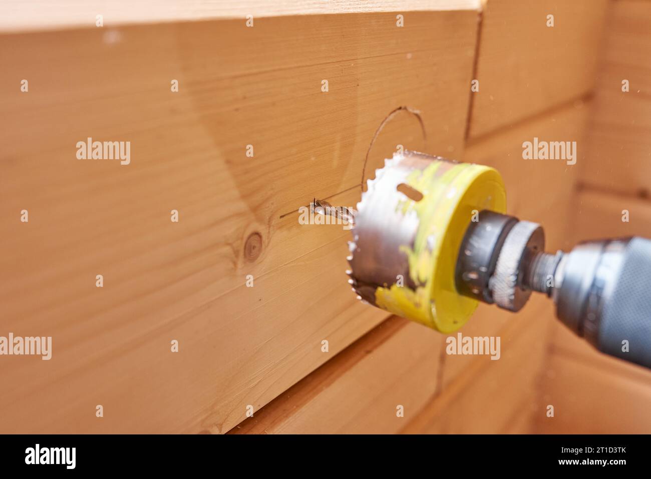 drill with crown making hole in wooden wall for electric cable, socket ...