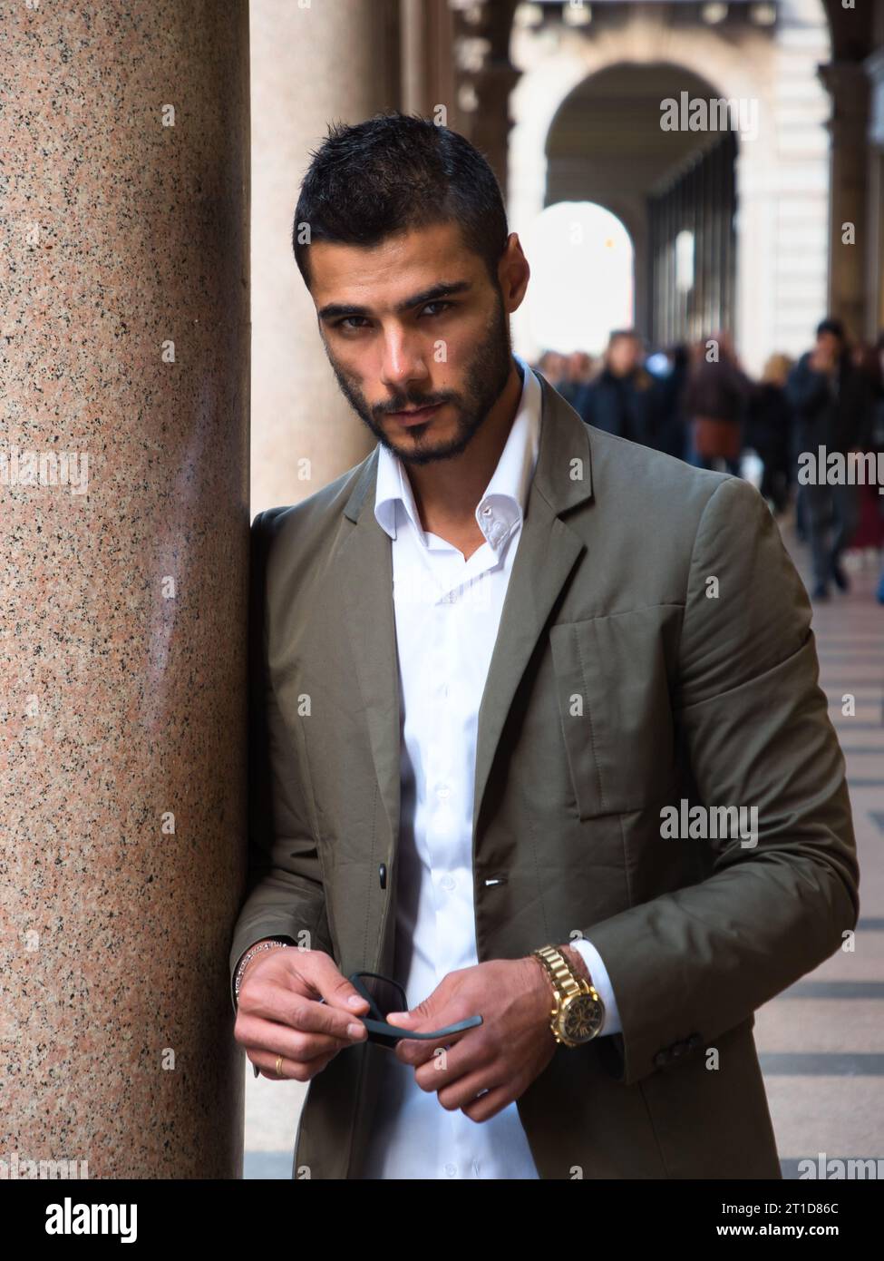 A man in a suit leaning against a pillar. Photo of a stylish man ...
