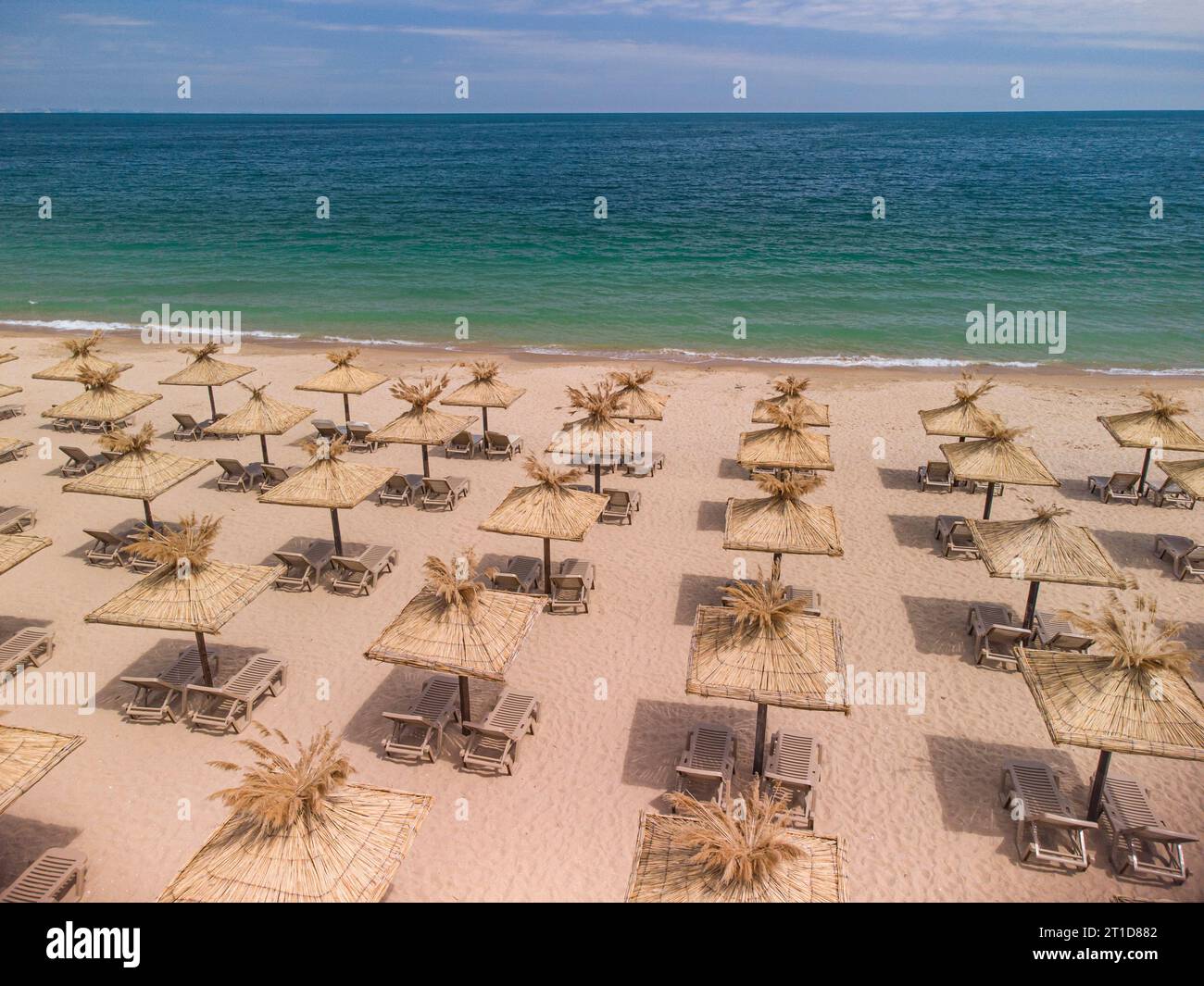 Aerial view of an amazing empty sand beach with straw beach umbrellas ...