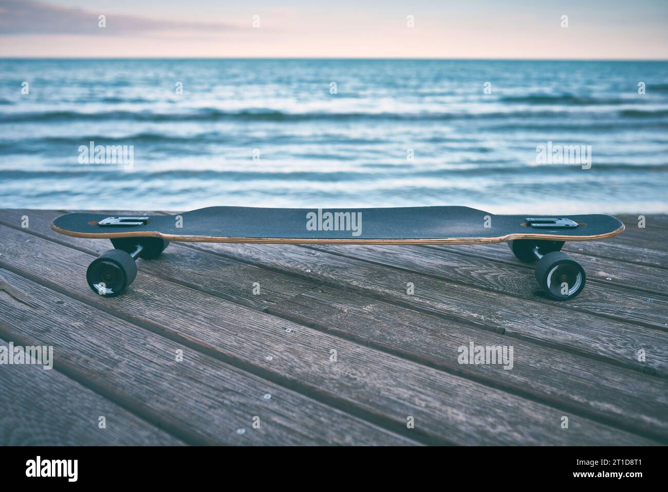 double kick cutaway longboard on wooden pier against the background of ...