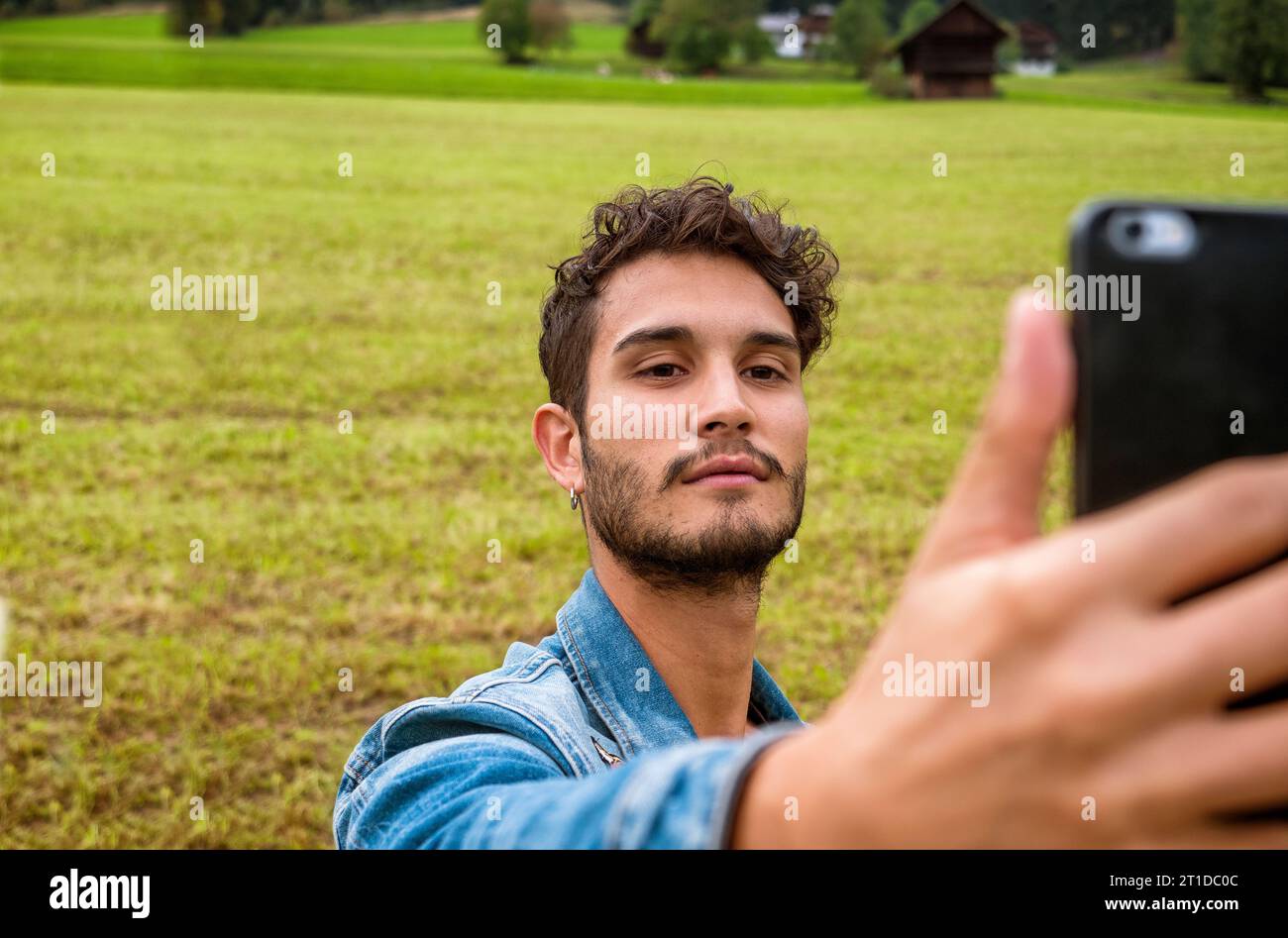 A man taking a picture of himself with a cell phone. Photo of a man taking a selfie with his ...