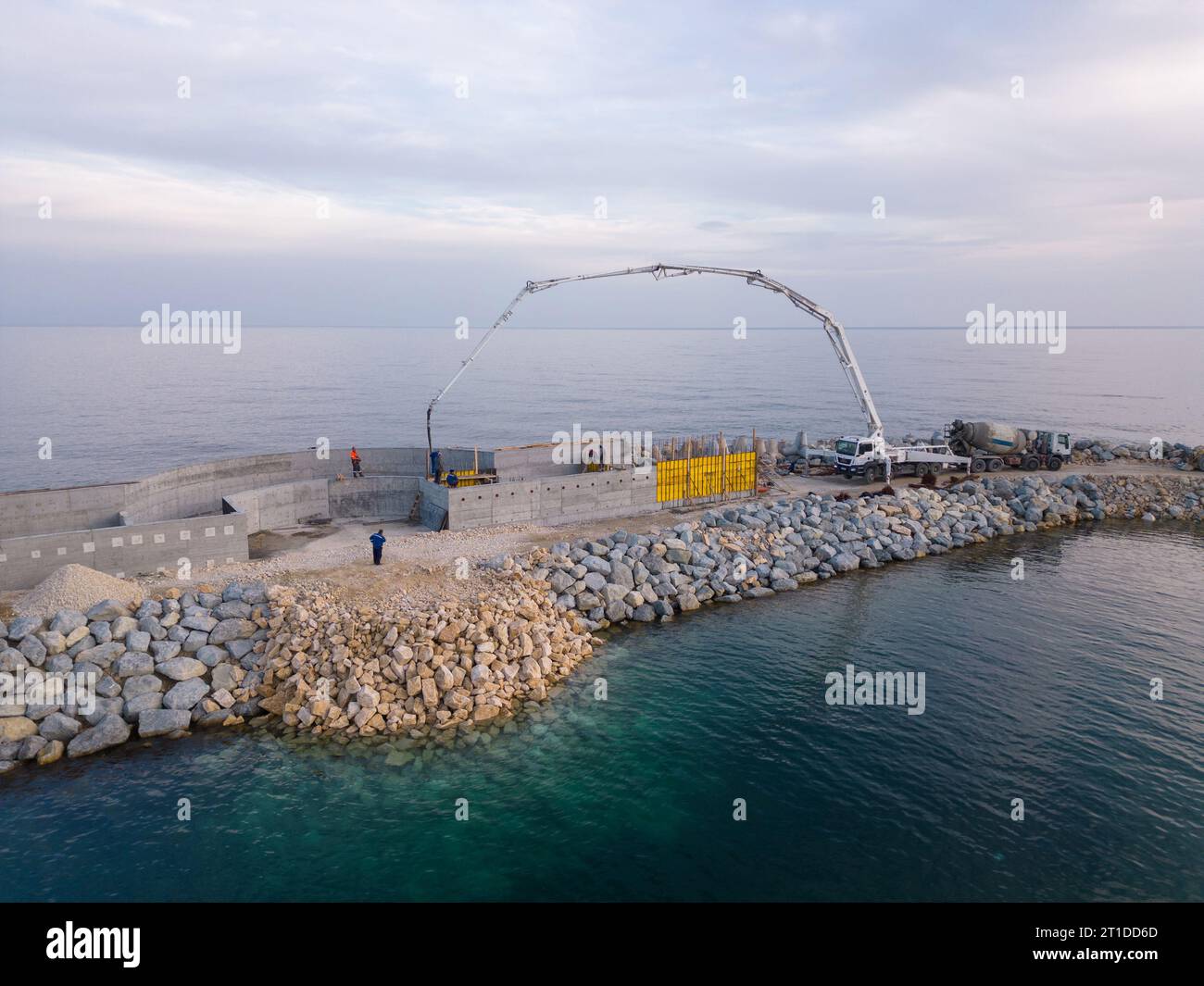 Heavy construction equipment is building a breakwater. Pouring concrete ...