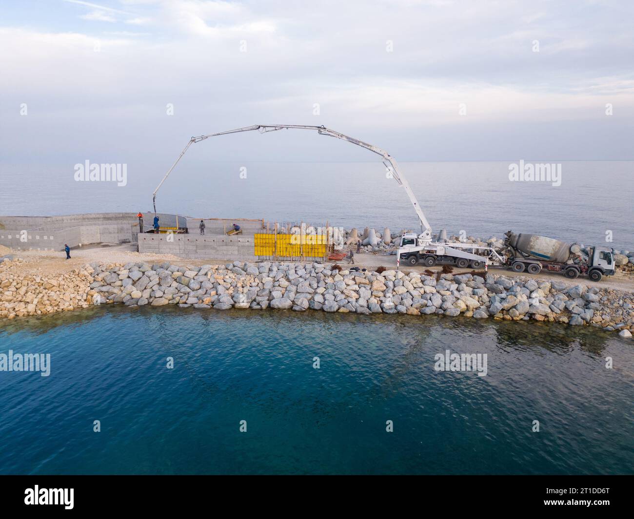 Heavy construction equipment is building a breakwater. Pouring concrete ...