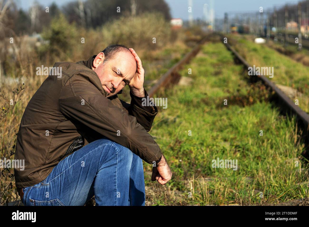 The thoughtful man sits on rails. The upset person in a stress. Concept ...