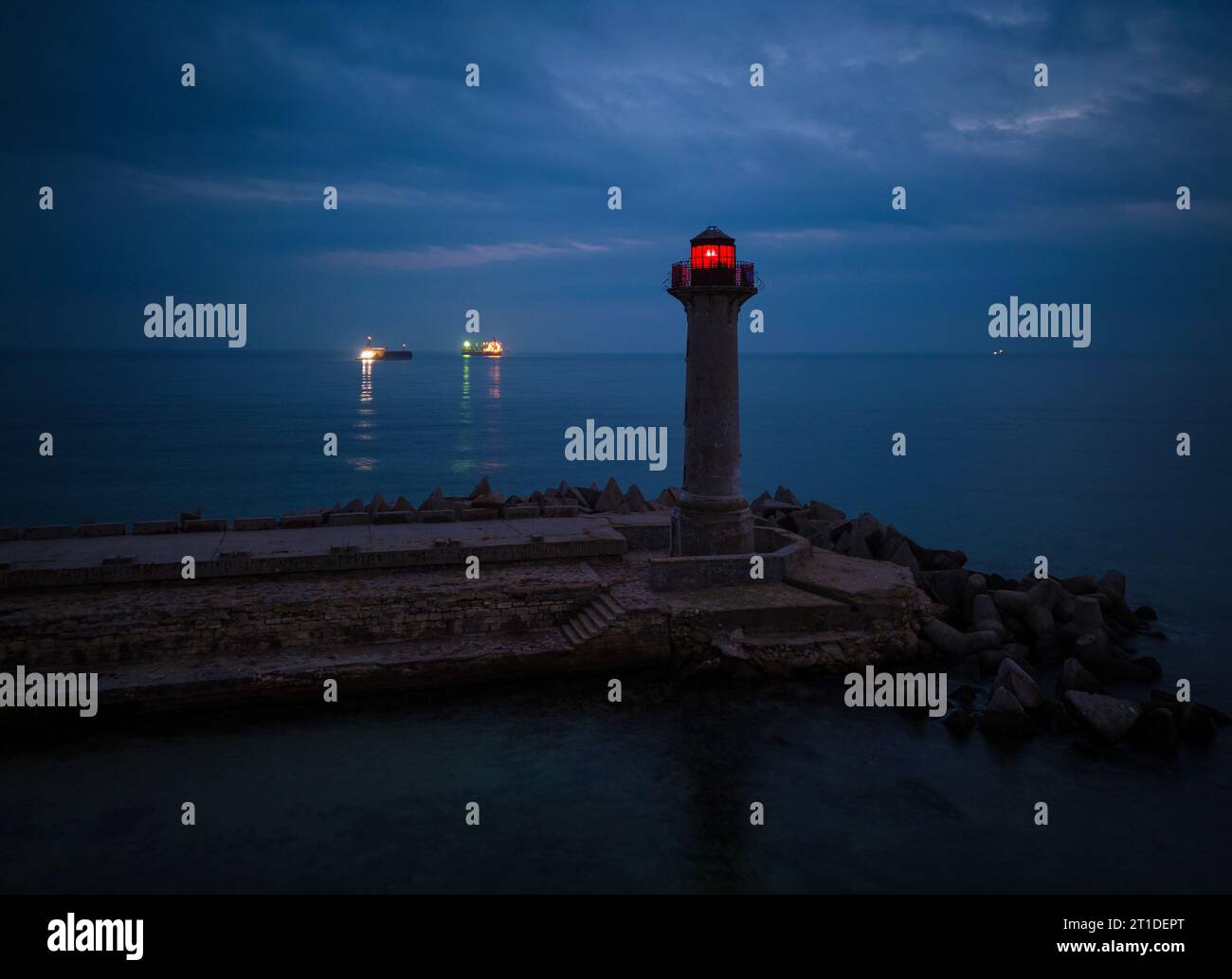 lighthouse on the seashore with red light at night against the ...