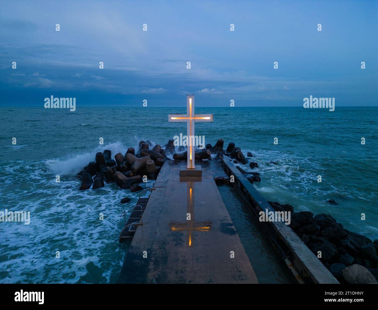 christian cross standing on pier in the stormy sea or ocean with ...