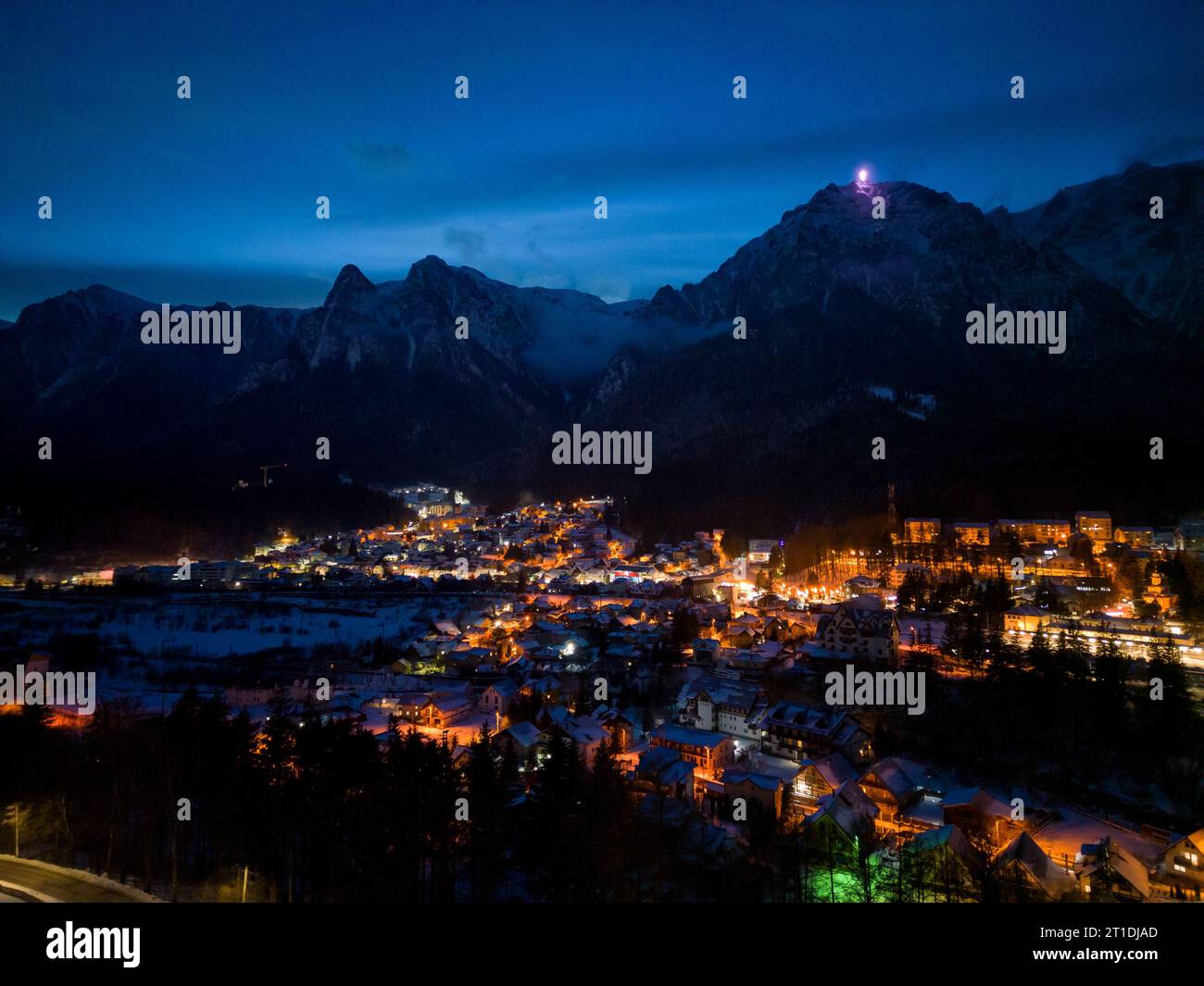 Aerial top view of Busteni city covered with snow in winter at night ...