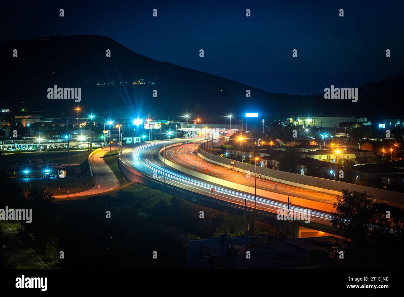 A nighttime scene on a busy highway with a majestic mountain backdrop ...