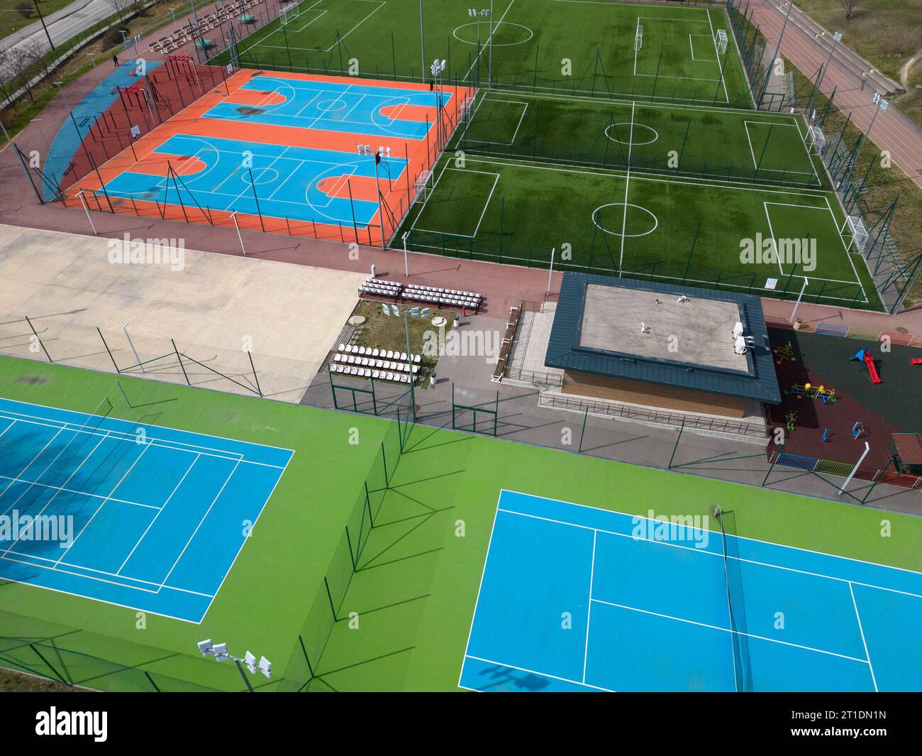 aerial view of a green football field, colorful basketball courts, and ...