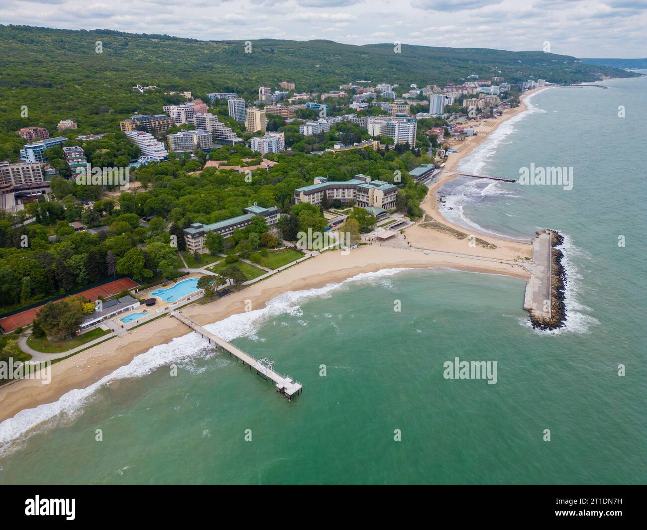 Aerial top view of a long pier extending into the sea, located at a ...