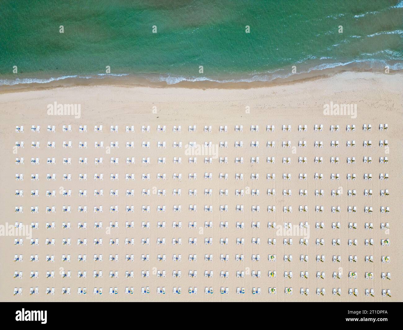 A sandy beach stretches along the seaside, adorned with empty sun ...