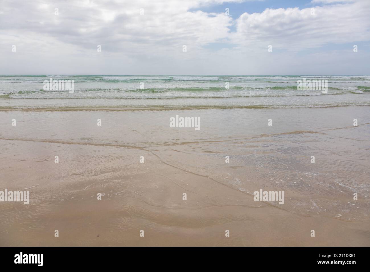 Under a cloudy sky, restless waves roll and crash upon the shore Stock ...