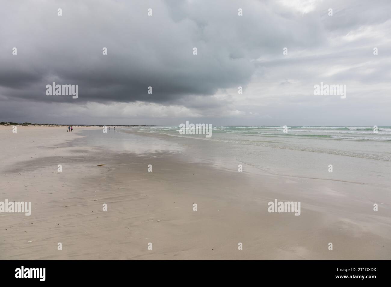 A vast beach is blanketed by grey, stormy clouds, and their reflection ...