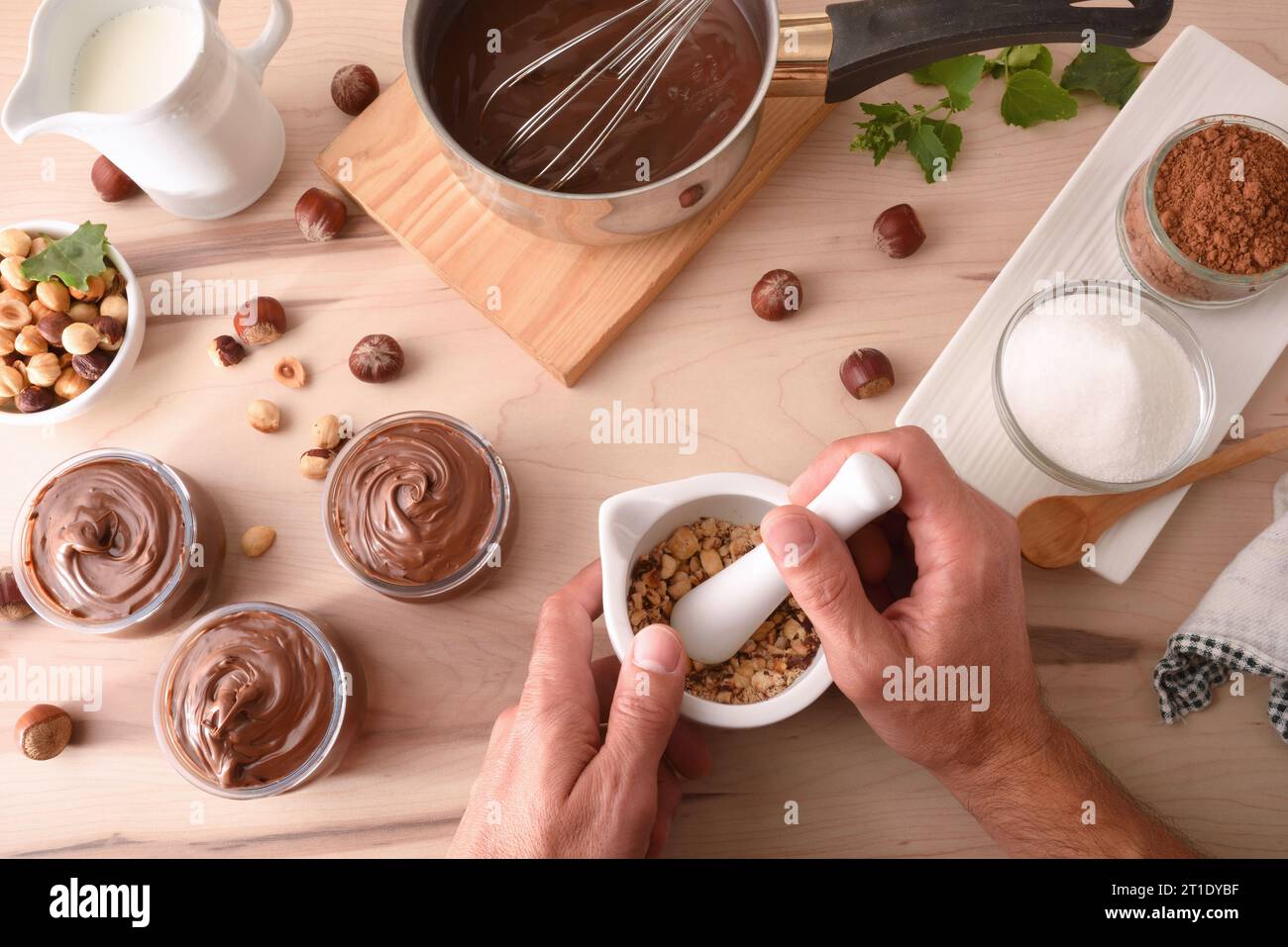 Making chocolate and hazelnut cream with hands crushing hazelnuts in a ...