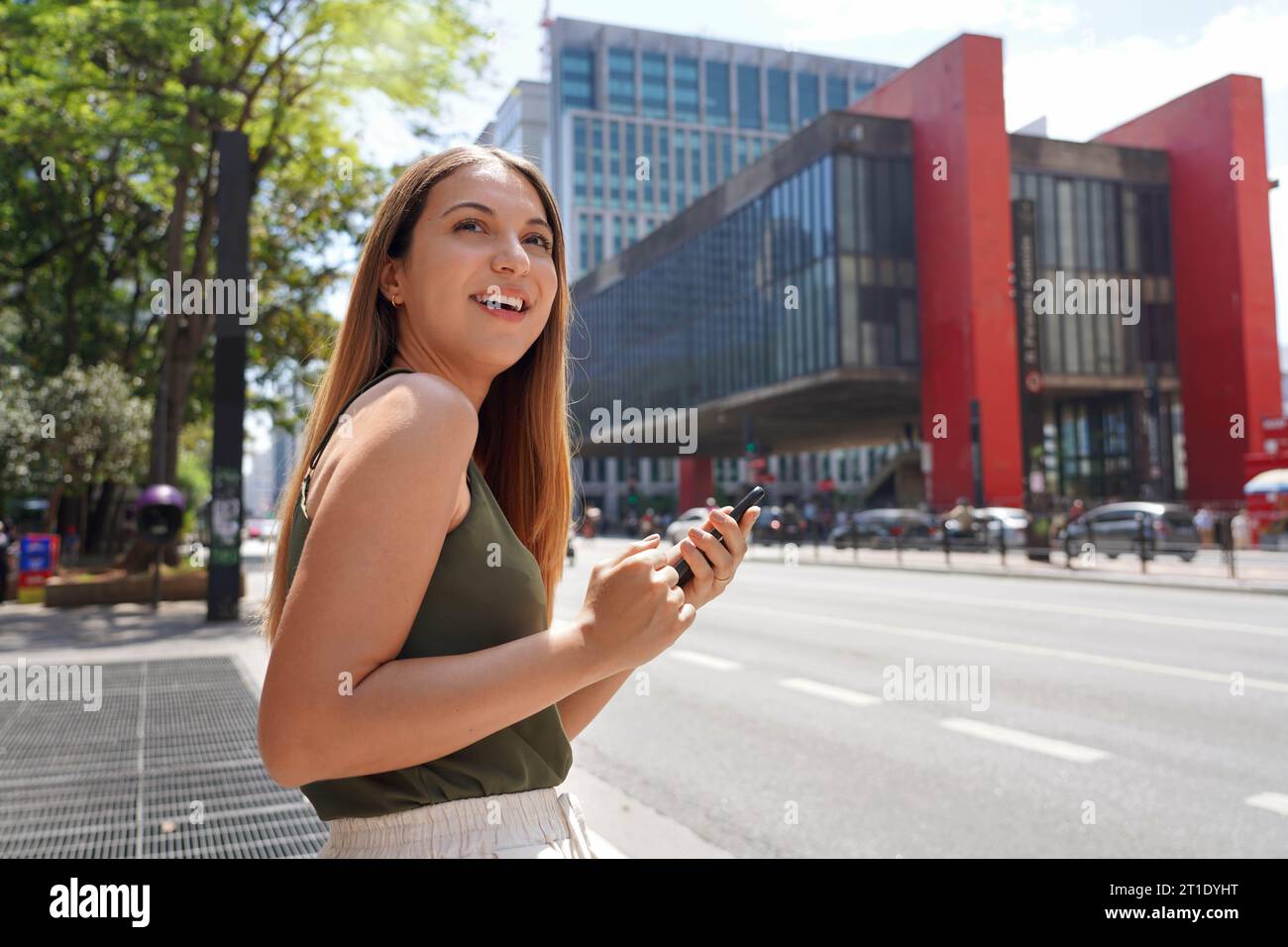 Smiling Brazilian woman hail a vehicle using mobile app waiting for ...