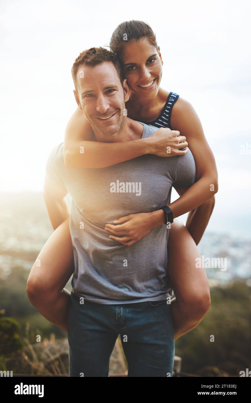 Portrait, piggy back and couple with hug, outdoor or lens flare with ...