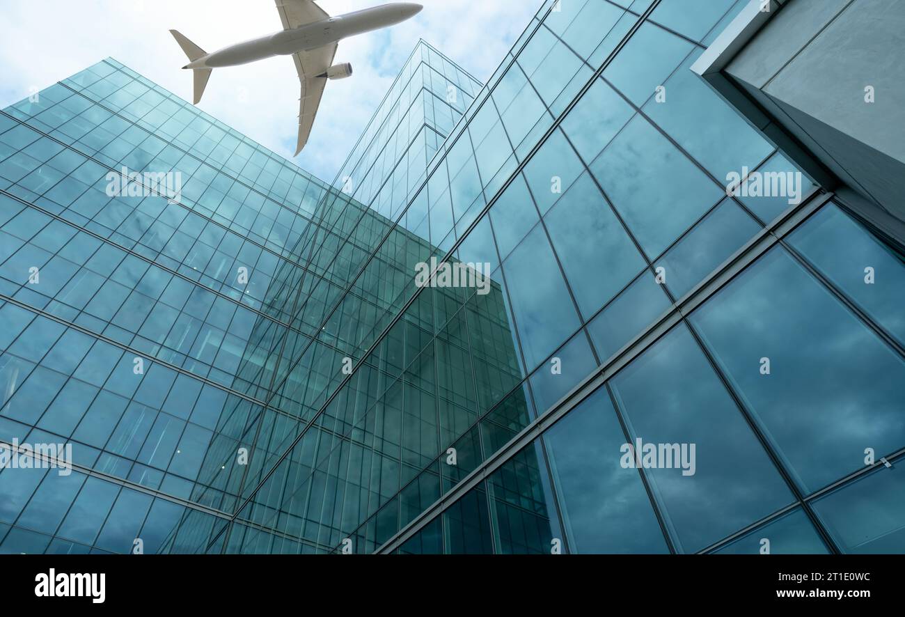 Airplane flying in the sky above modern sustainable glass office ...