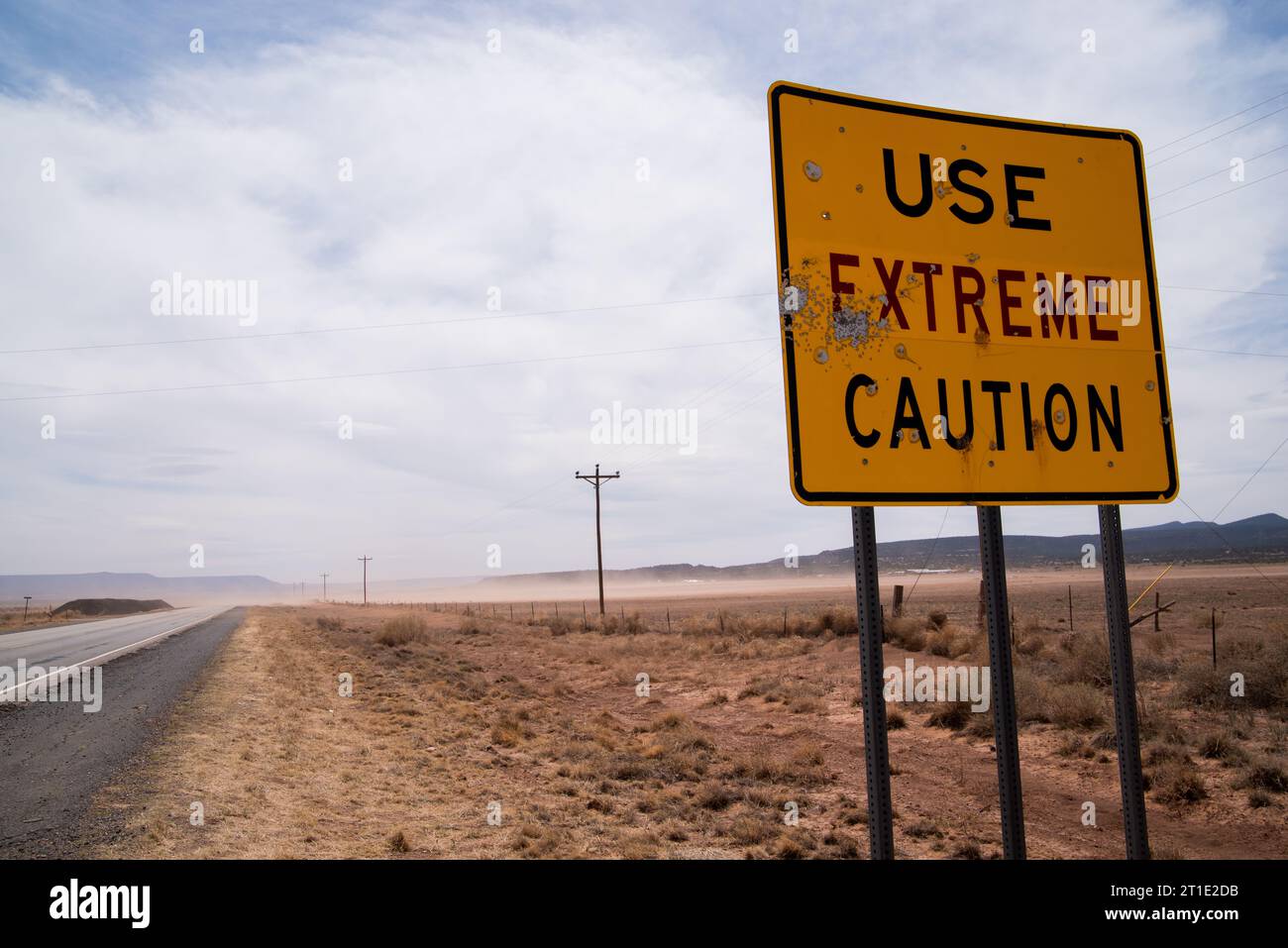 Traffic sign with impacts of gun buckshot reading USE EXTREME CAUTION ...