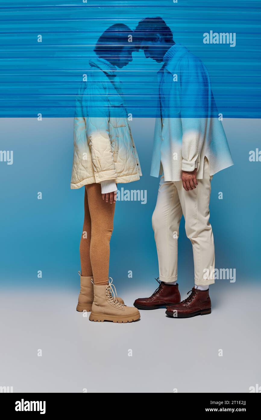 side view of multiethnic models in winter attire posing head to head ...