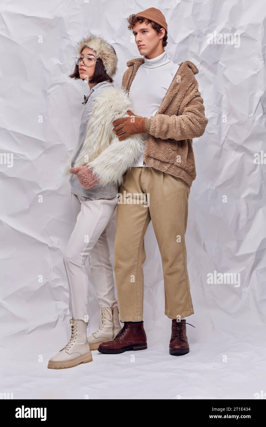 full length of multiethnic couple in worm cozy outfits looking away on ...