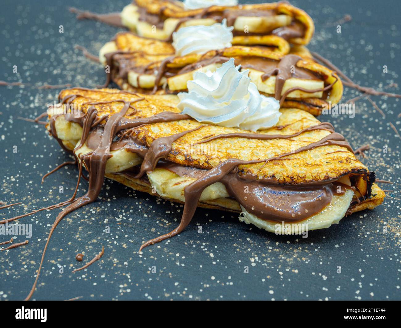 delicious thin pancakes with chocolate spread and slices of banana ...