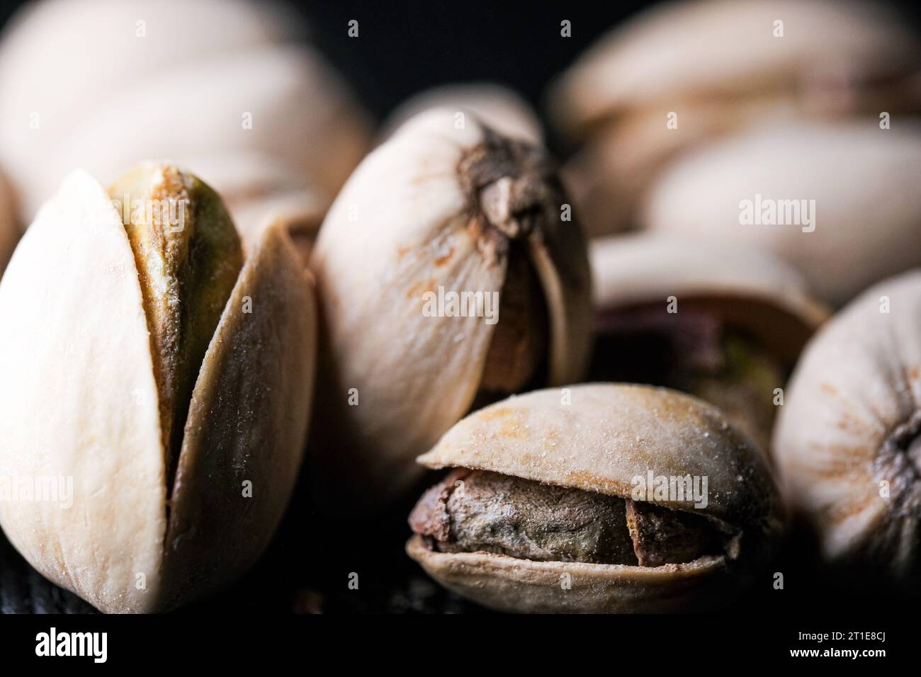 Close-up of an assortment of brown nuts in their shells on a dark ...