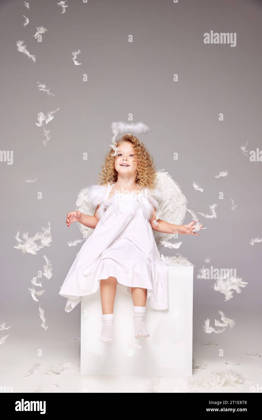 Happy, smiling, positive little girl, child in costume of angel sitting ...