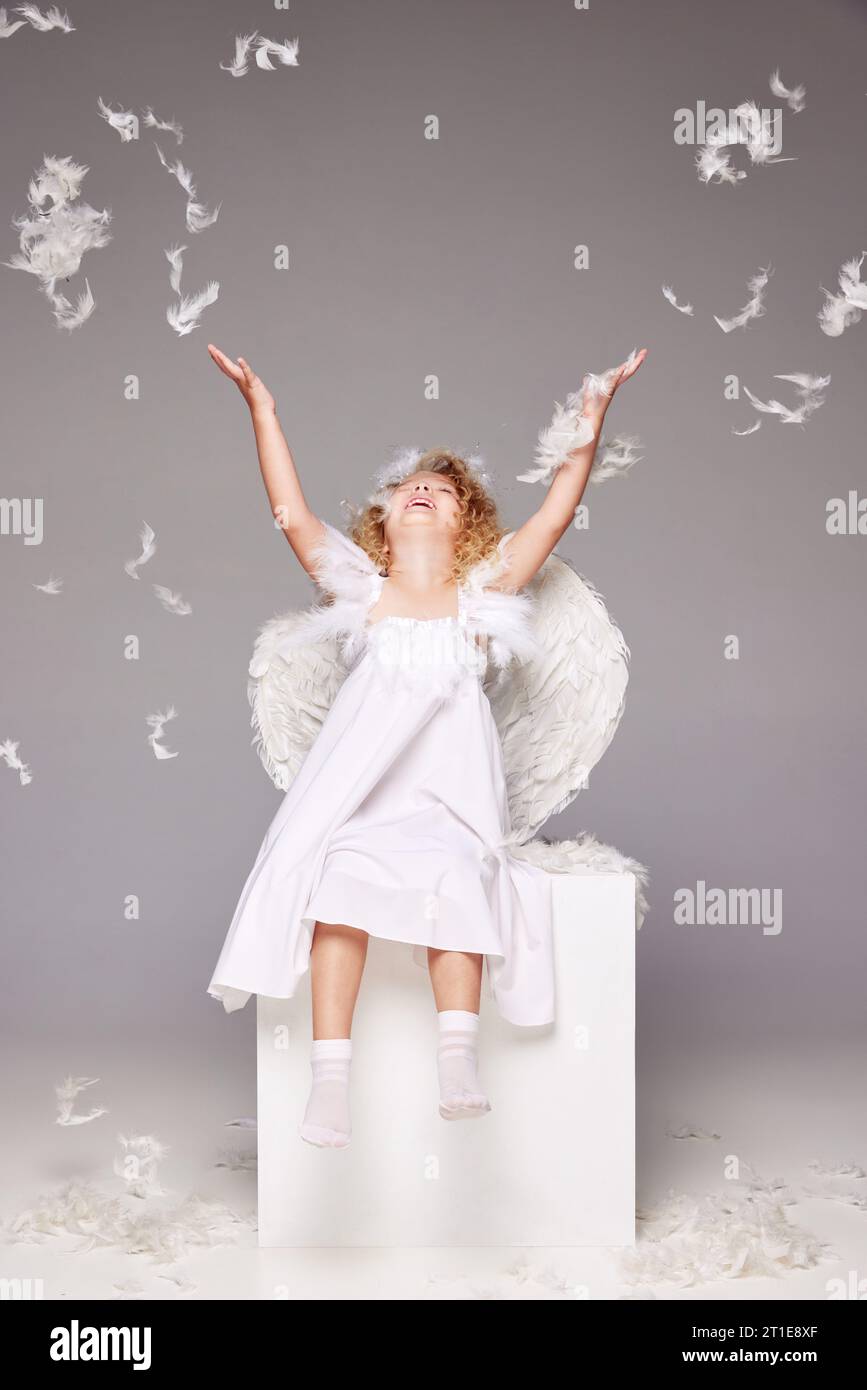 Happy, smiling, positive little girl, child in costume of angel sitting ...