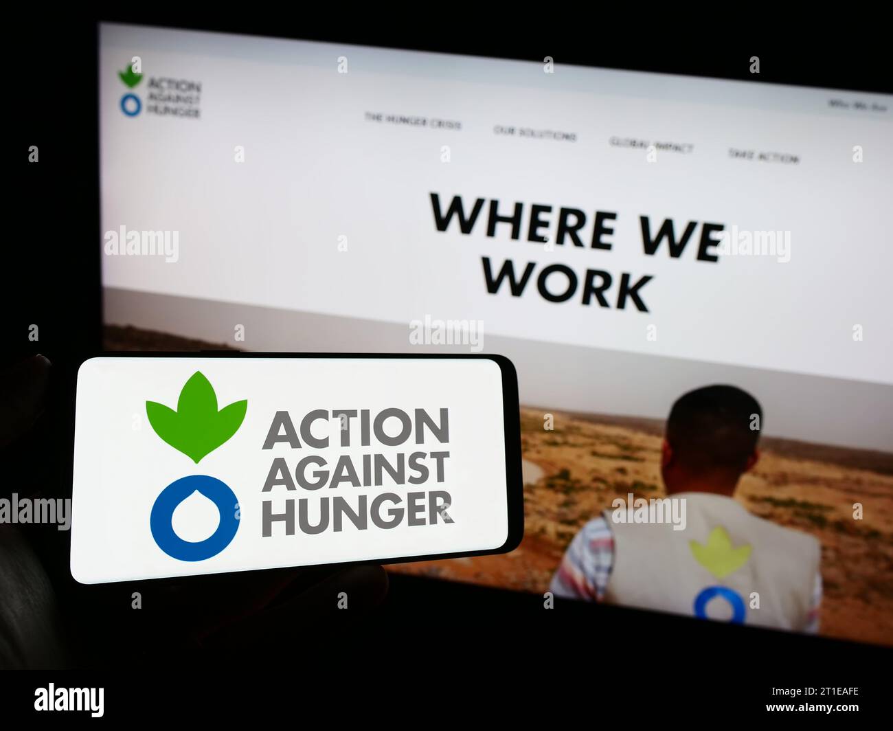 Person holding mobile phone with logo of humanitarian organization ...