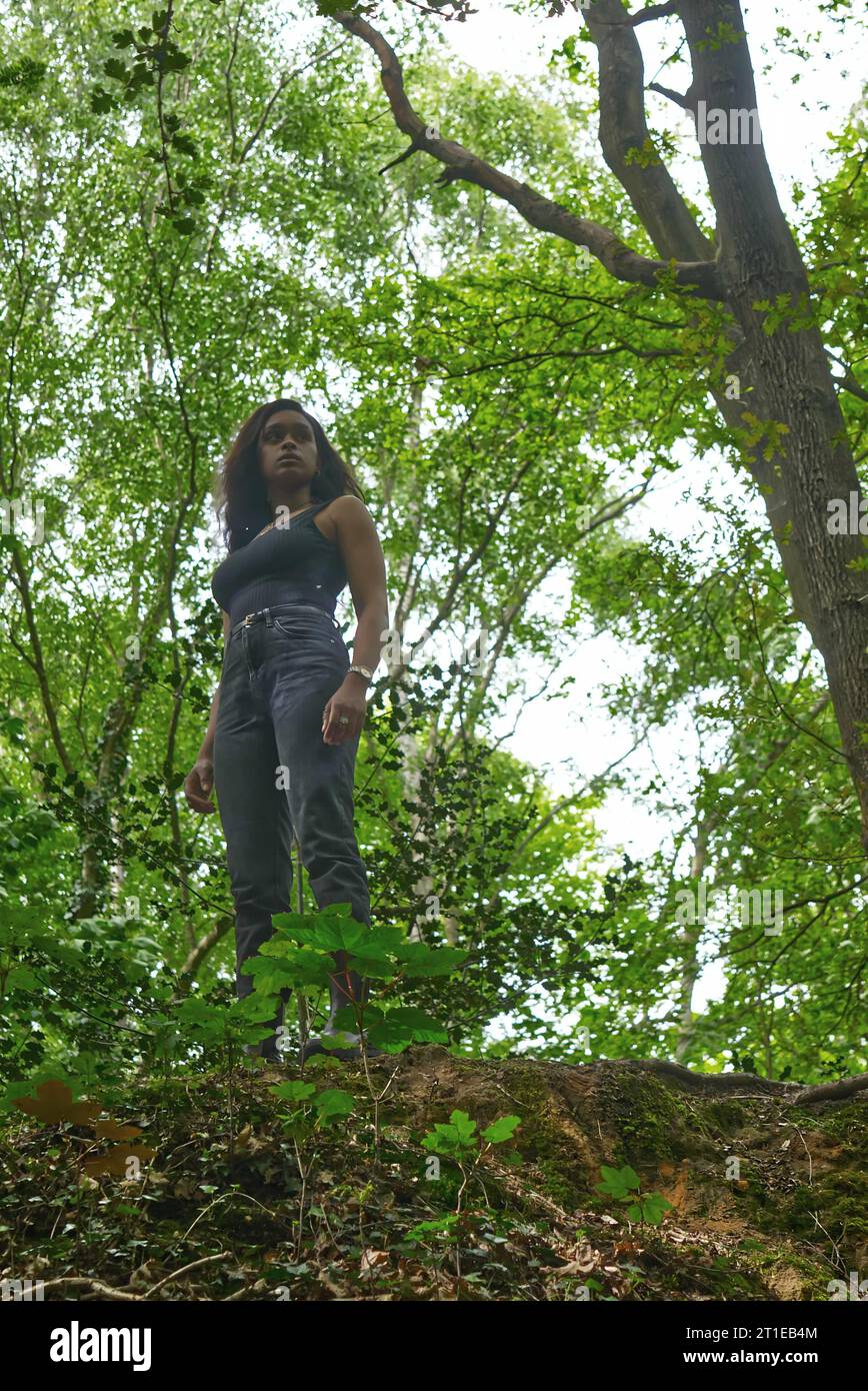 A young black woman standing at the edge of a deep drop in a wood Stock ...